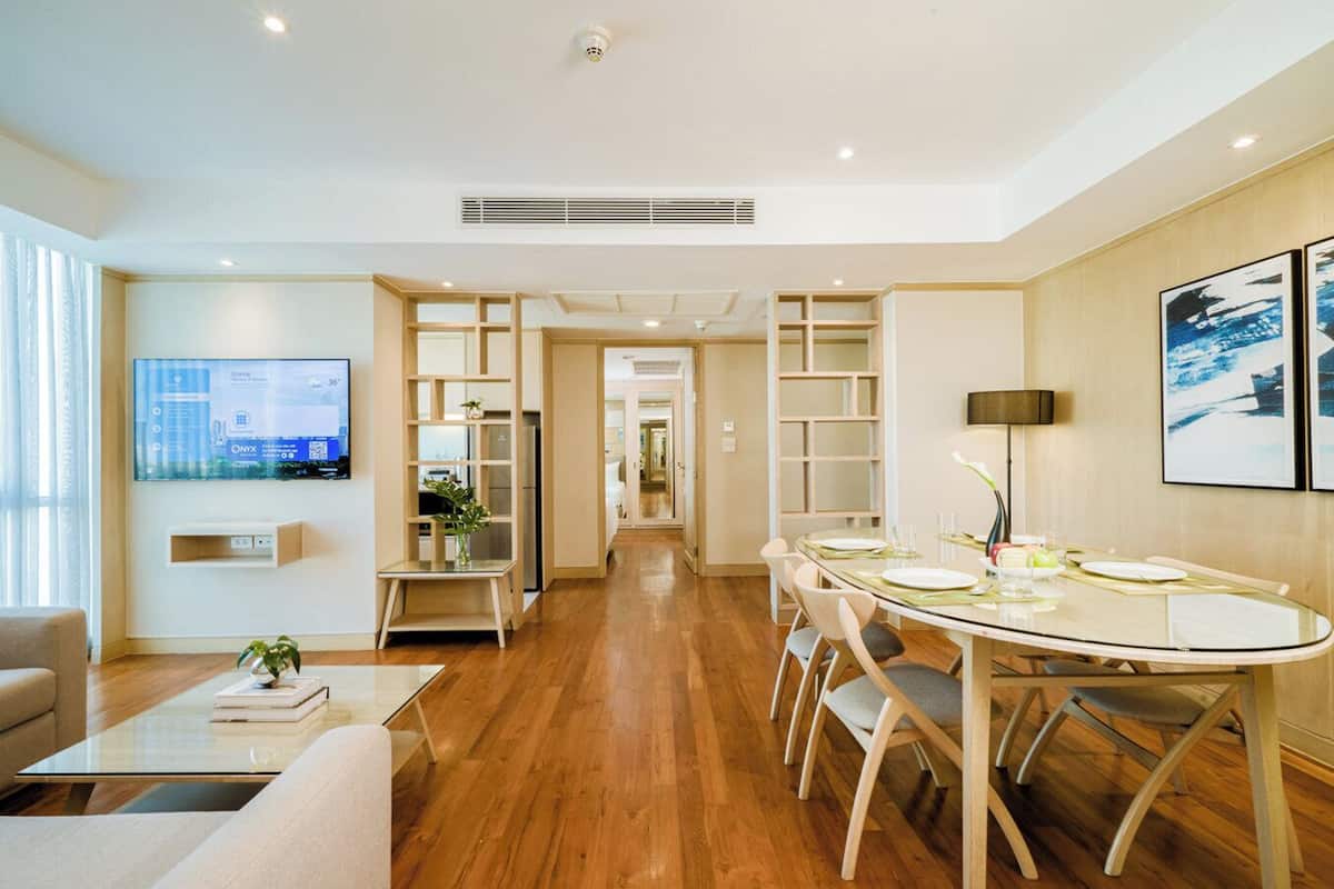 Uma sala de estar moderna com uma mesa de centro de vidro, um sofá e um espaço de refeições com uma mesa e cadeiras de vidro.