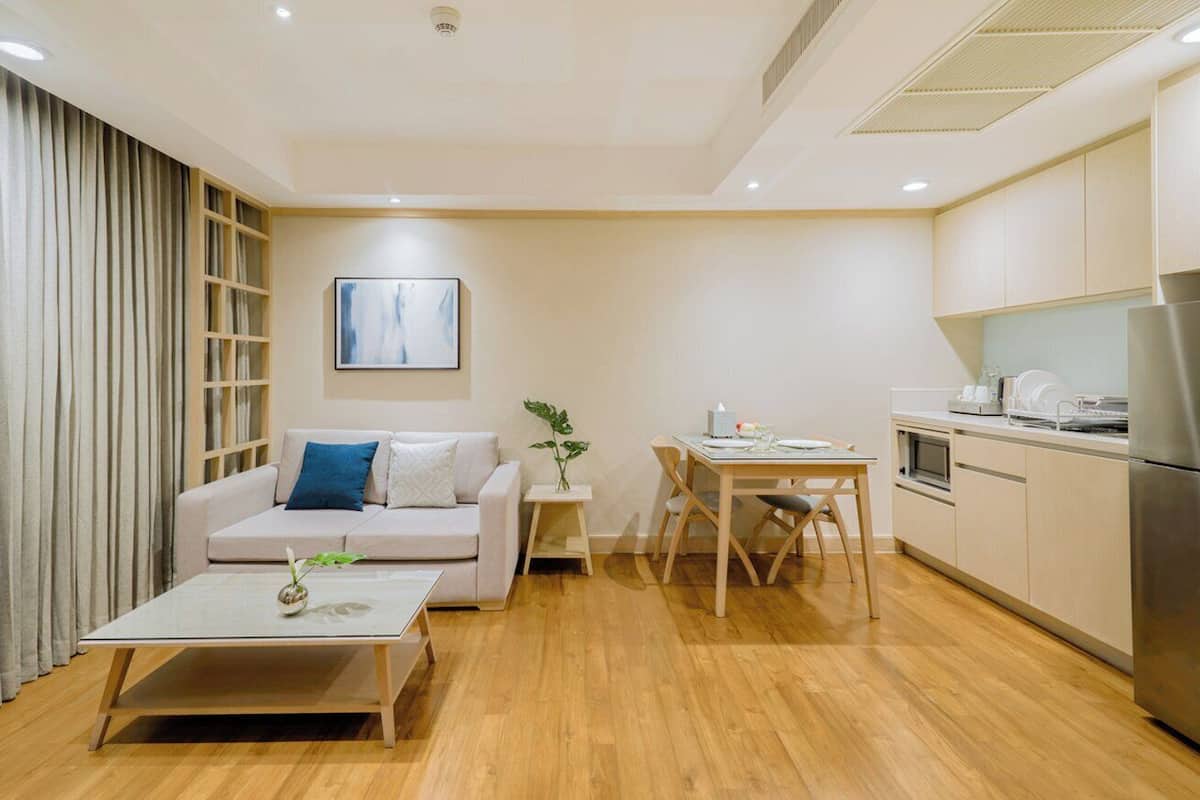 Uma sala de estar moderna com sofá, mesa de centro e área de jantar. Há uma cozinha equipada com frigorífico e micro-ondas.