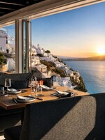Mesa posta para refeição, com vista para uma cidade costeira e o mar.
