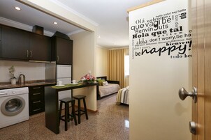 Quarto de hotel compacto com cozinha compacta, uma cama e banheiro.