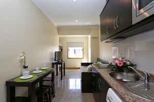 Cozinha compacta com área de refeições, forno embutido e pia.