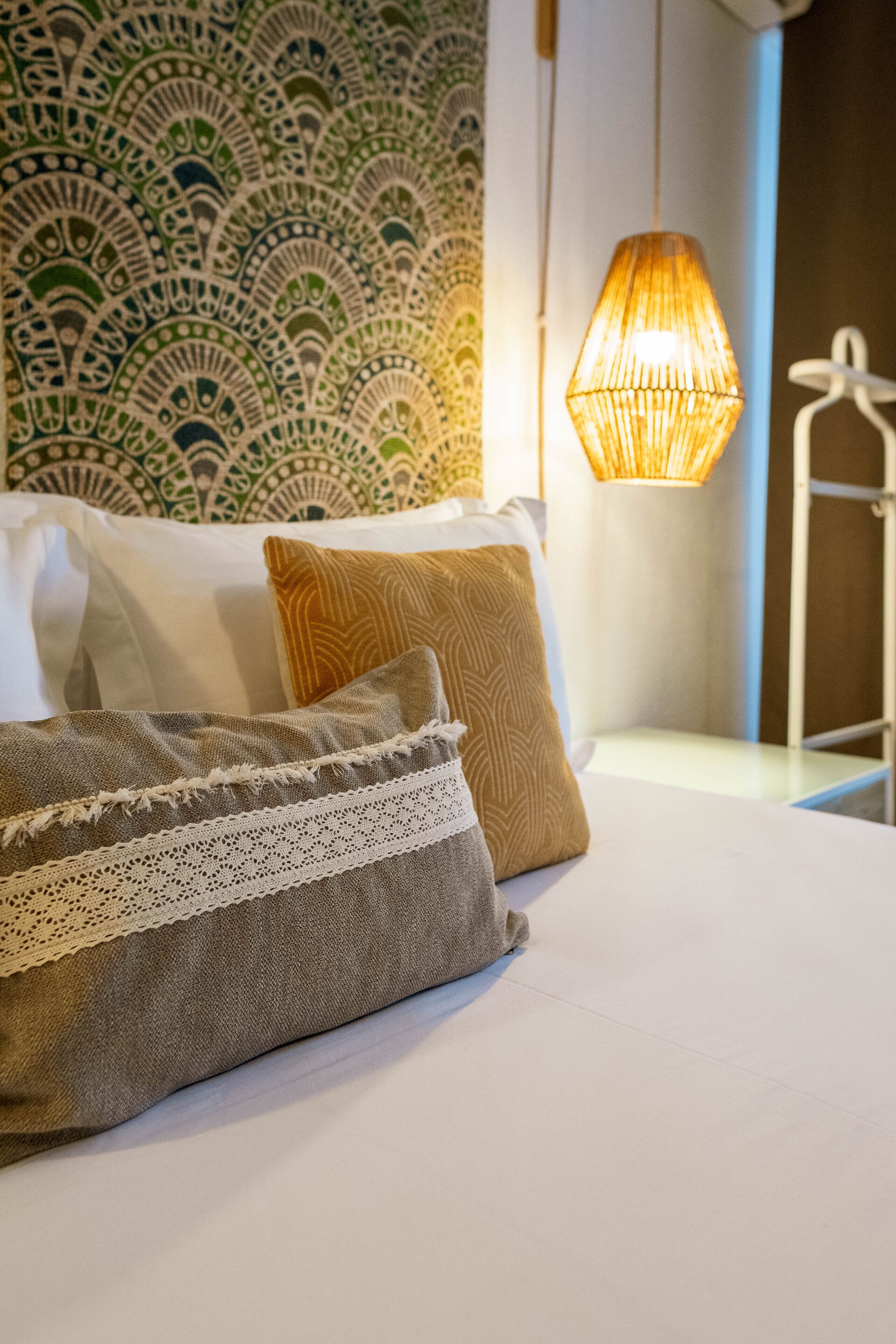 Uma cama bem arrumada com almofadas estampadas e uma parede decorativa ao fundo.