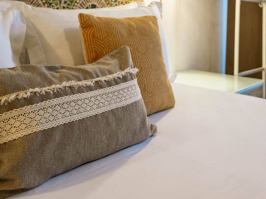 Uma cama bem arrumada com almofadas estampadas e uma parede decorativa ao fundo.