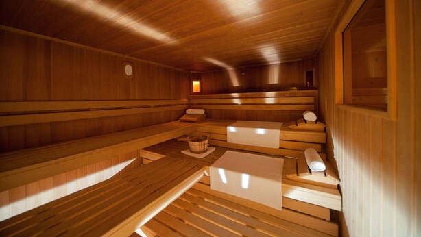 Uma sauna com bancos e assentos de madeira, piso e teto de madeira.