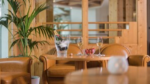 Interior em madeira com uma mesa posta para dois, incluindo uma garrafa de champanhe, dois copos e uma taça de morangos.