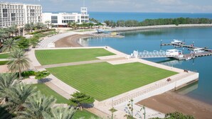 Um hotel à beira-mar com um extenso jardim, um porto de iates e vista para o mar.