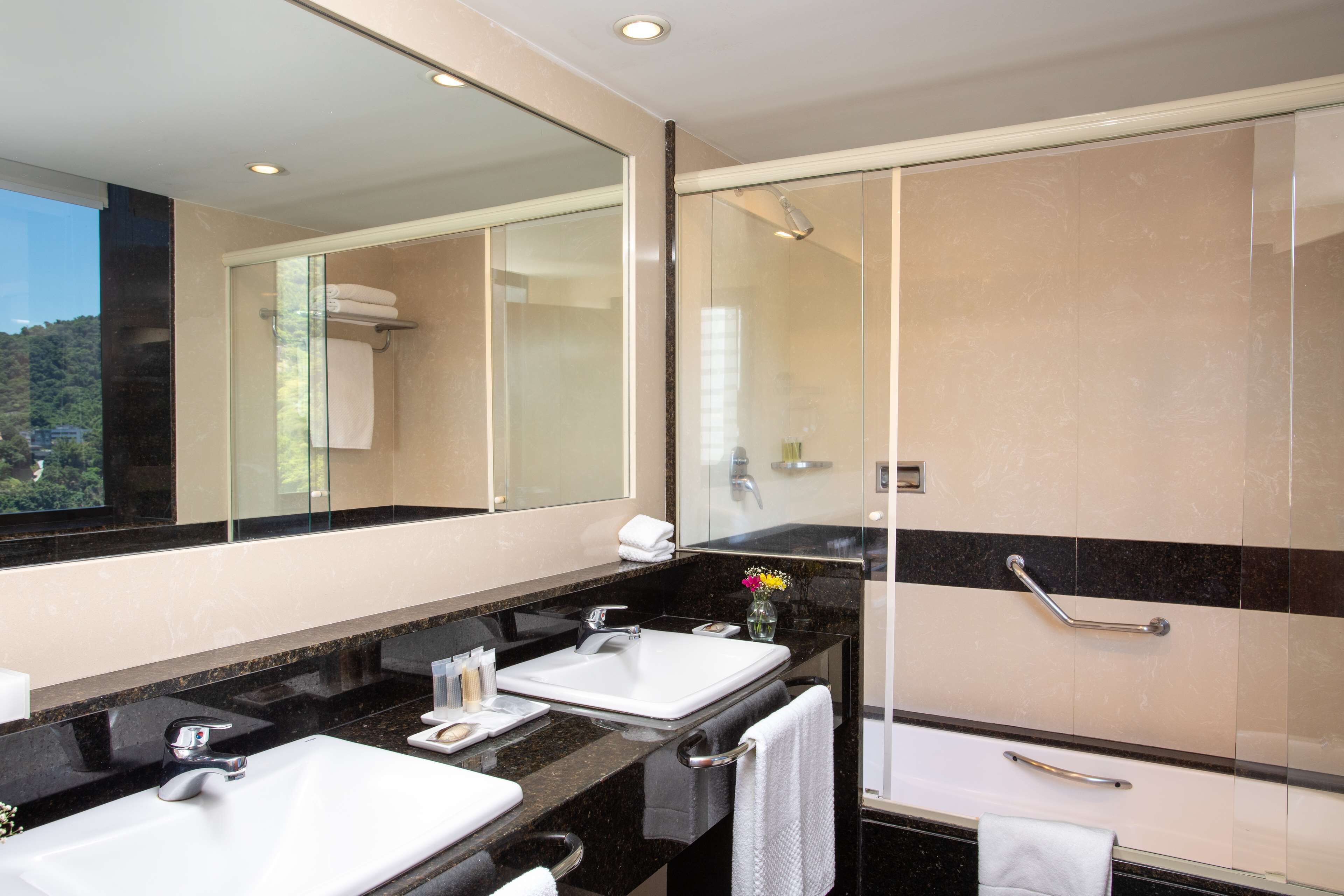 Uma casa de banho moderna com duas pias, um espelho grande e cabine de duche em vidro.