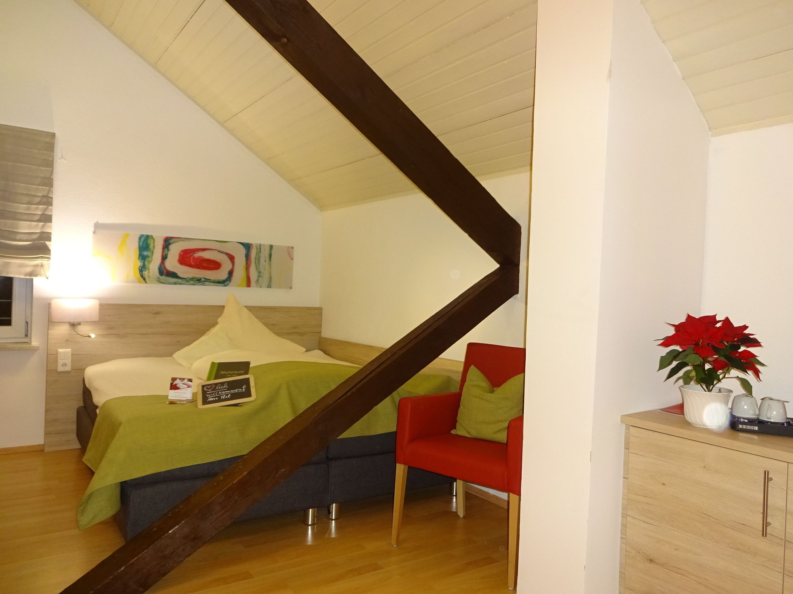 Quarto com cama, uma cadeira vermelha, um armário de madeira e escada.