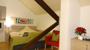 Quarto com cama, uma cadeira vermelha, um armário de madeira e escada.