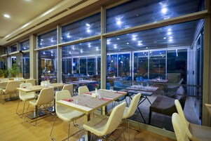 Um restaurante amplo com tetos altos, grandes janelas e mobiliário moderno.