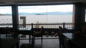 Restaurante com vista para um lago e montanhas.