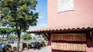 Um edifício com fachada desgastada, um mostrador de sol e placas indicando 'Agriturismo La Meridiana'.