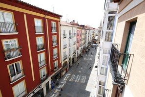 Vista da rua de uma cidade europeia, com edifícios altos, varandas e pedestres.