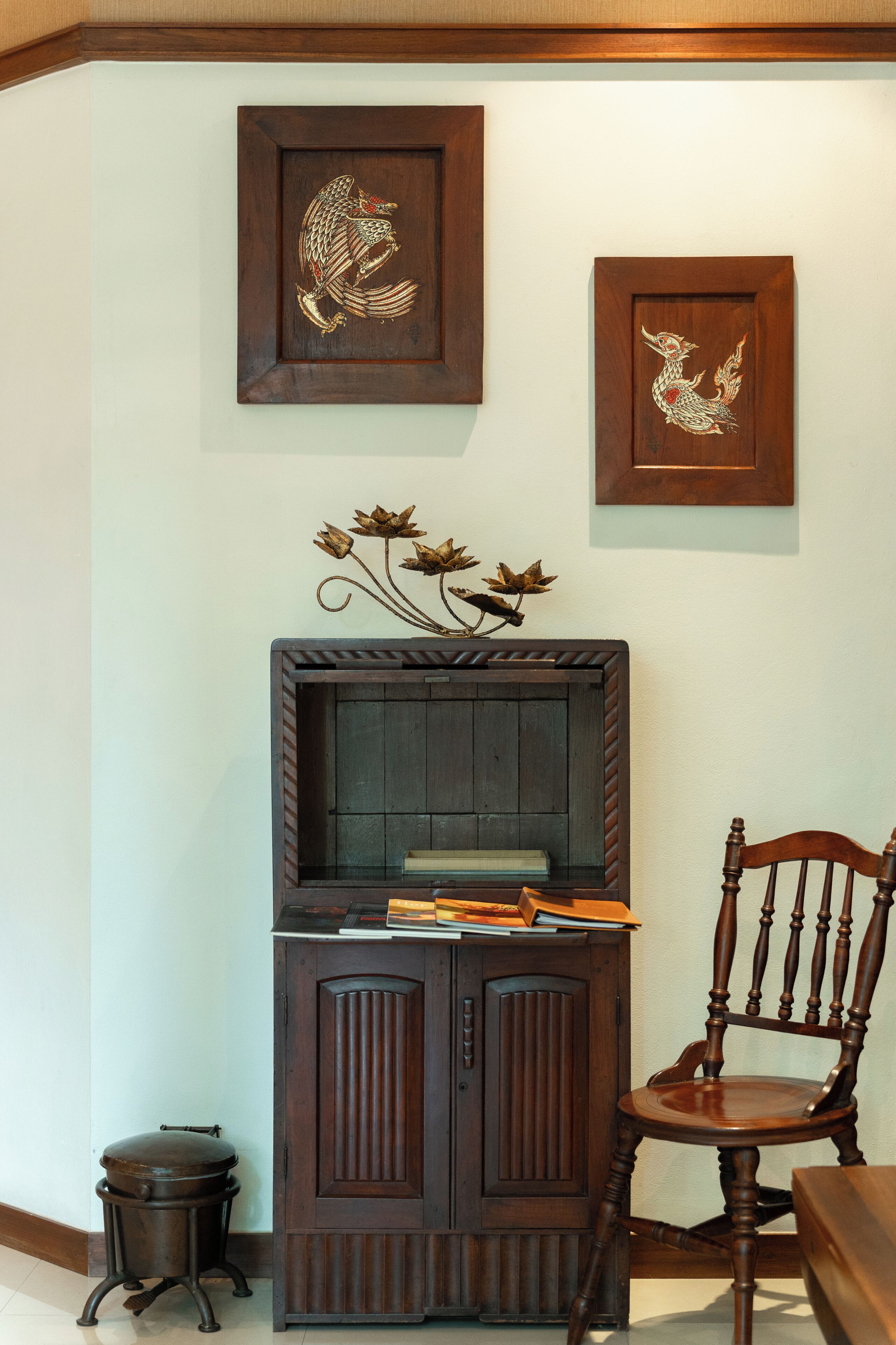 Quarto de canto com um armário de madeira, uma cadeira e duas obras de arte emolduradas na parede.