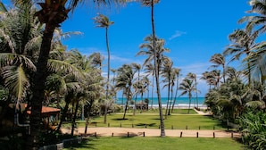 Resort tropical com palmeiras, praia e céu azul límpido.