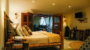 Quarto com uma cama grande, móveis de madeira, uma TV e uma escrivaninha.