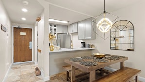 Uma cozinha moderna com uma mesa de jantar de madeira, bancos e uma luminária pendente exclusiva.