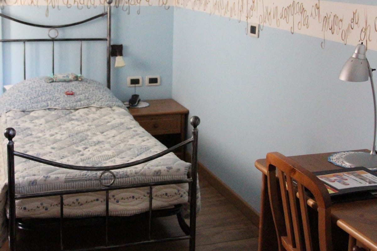 Quarto com cama, escrivaninha e cadeira.