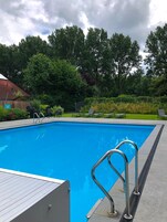 Piscina retangular com escadas de metal em um dos lados, ladeada por um deck de concreto.