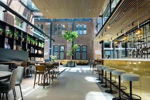Um interior moderno com área de bar, assentos e uma grande janela com vista para um edifício de tijolos.
