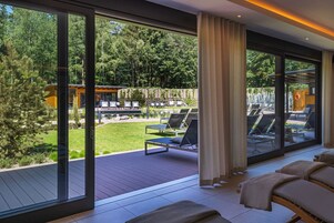Quarto moderno com amplas janelas para piscina e área de estar externa.