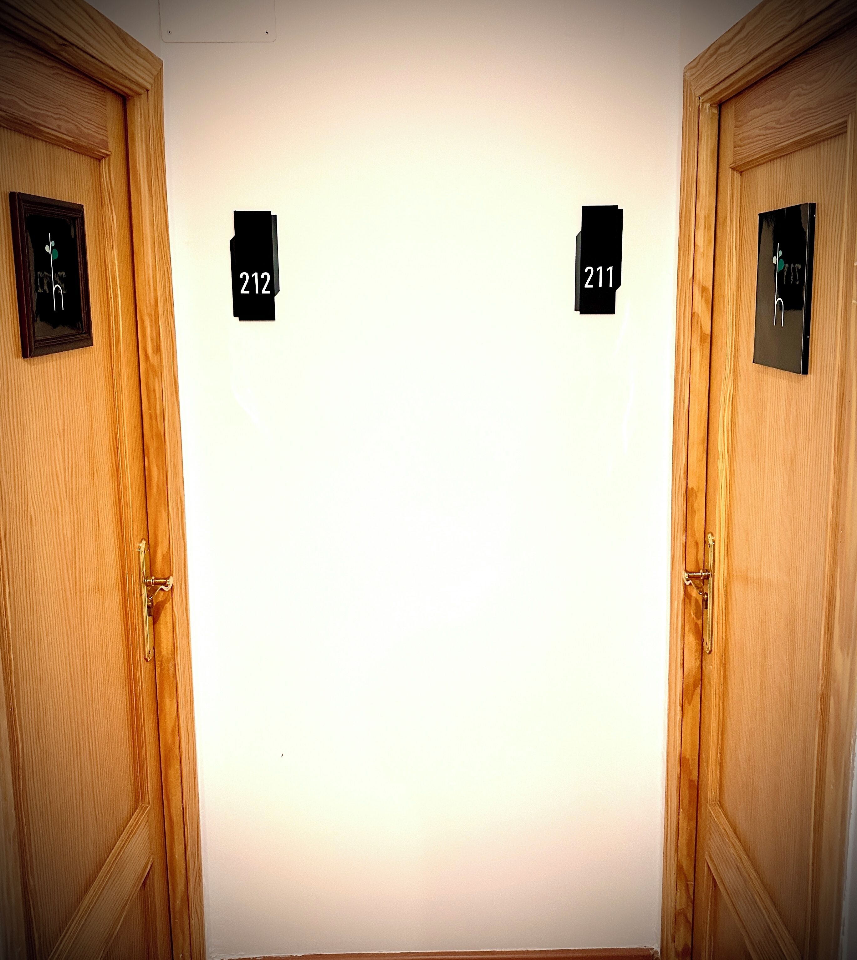 Duas portas de madeira com placas pretas numeradas, uma com o número 211 e outra com o número 212, indicando os números dos quartos.