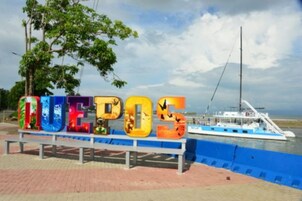 Um sinal com a palavra 'CUEPOS' em letras coloridas, um barco ao fundo e uma barreira azul.