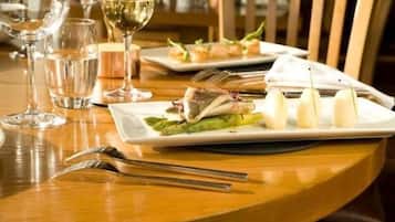 Uma mesa de jantar com pratos de comida, copos de vinho e talheres.
