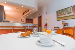 Mesa de café da manhã com croissants, suco de laranja e xícaras de café.