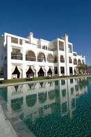 Um hotel com vários andares e uma piscina na frente.
