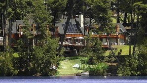 Uma propriedade à beira do lago com vários edifícios, áreas de estar ao ar livre e um píer de barcos.