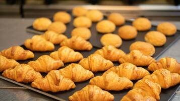 Uma bandeja com croissants recém-assados sobre uma superfície metálica.