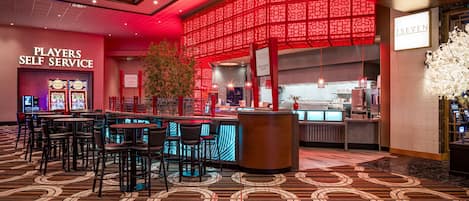 Um saguão de hotel com área de bar, espaço de recreação para crianças com serviço e restaurante.