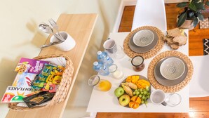 Uma mesa de madeira com uma cesta de lanches, frutas e bebidas para o café da manhã.