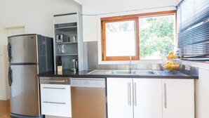 Uma cozinha moderna com eletrodomésticos de aço inoxidável, uma máquina de lavar louça e uma janela com persianas.