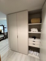 Um guarda-roupa branco com vários compartimentos, incluindo prateleiras e gavetas.