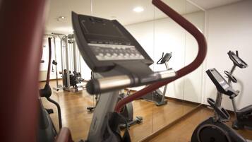 Equipamento de ginástica com visor digital, espelho e chão de madeira em uma academia.
