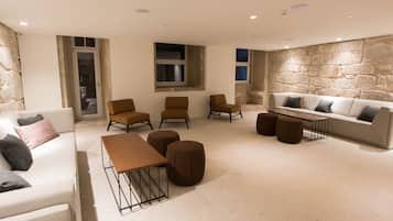 Uma sala de estar moderna com uma parede de destaque em pedra, um sofá branco e uma mesa de centro de madeira.