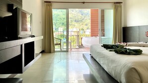 Quarto de hotel moderno com uma cama grande, televisão de tela plana e varanda com hidromassagem.