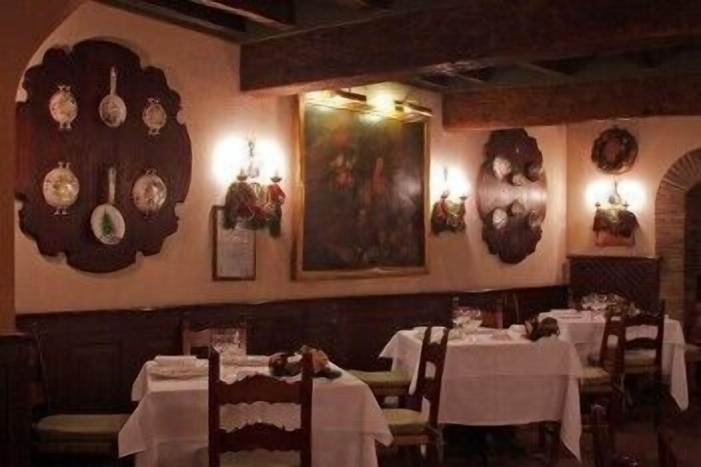 Interior de restaurante com paredes de madeira, obras de arte emolduradas e mesas preparadas para refeições.