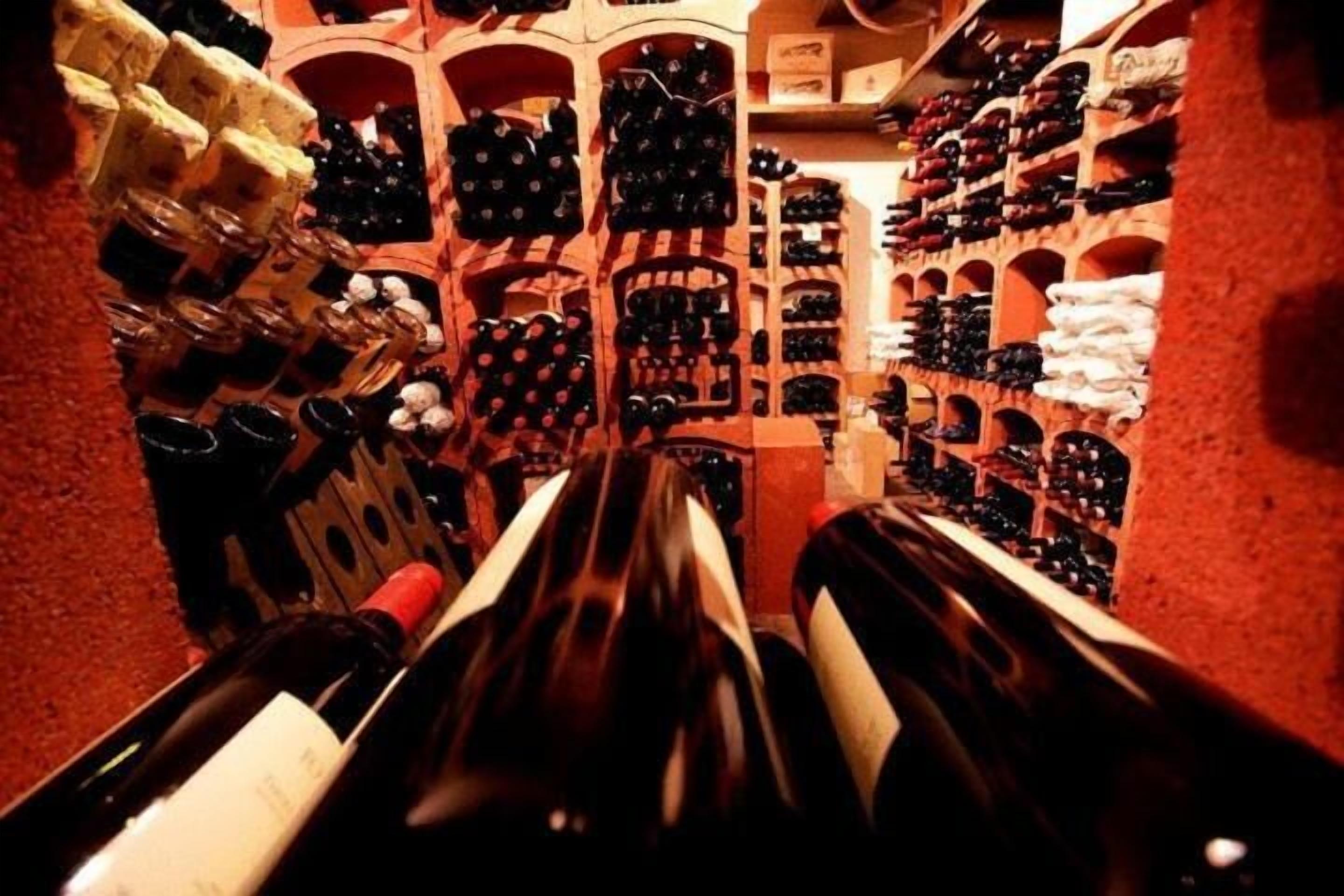Uma adega com fileiras de garrafas de vinho em prateleiras.