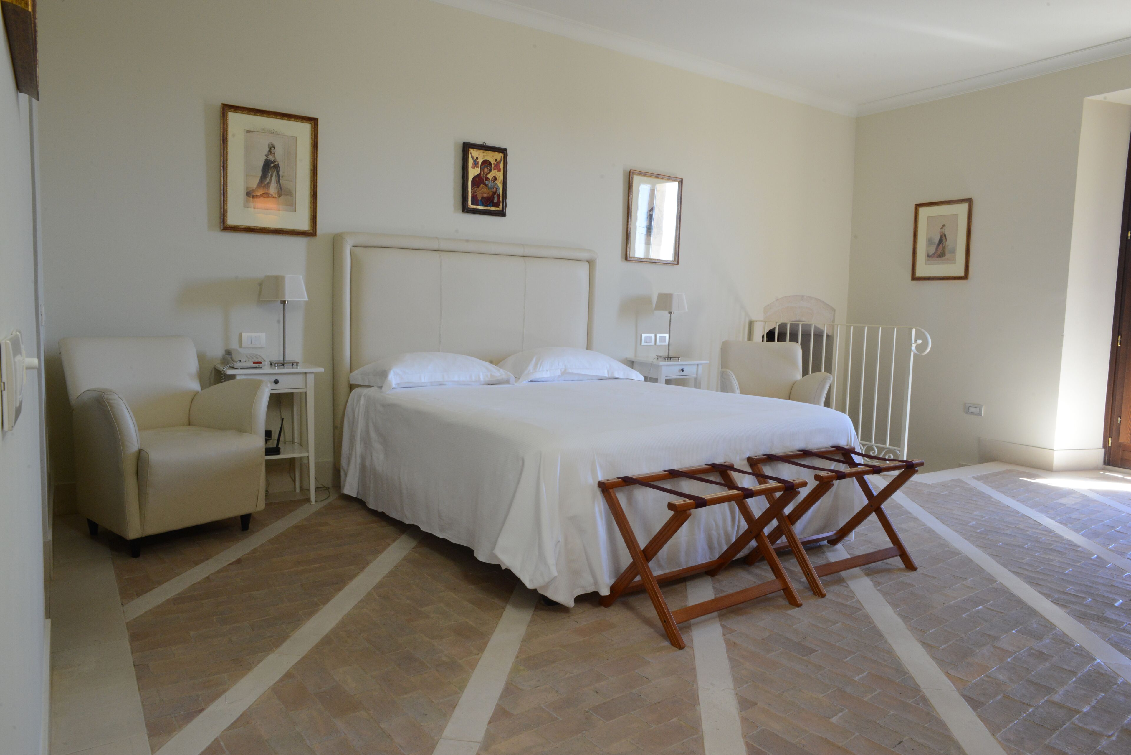 Quarto de hotel com uma cama grande, uma cadeira, uma mesa de cabeceira e um abajur.