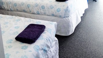 Quarto com beliches e duas camas de solteiro, cada uma com roupa de cama e almofadas estampadas.
