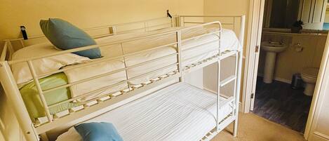 Uma cama beliche em um quarto com porta para um banheiro.