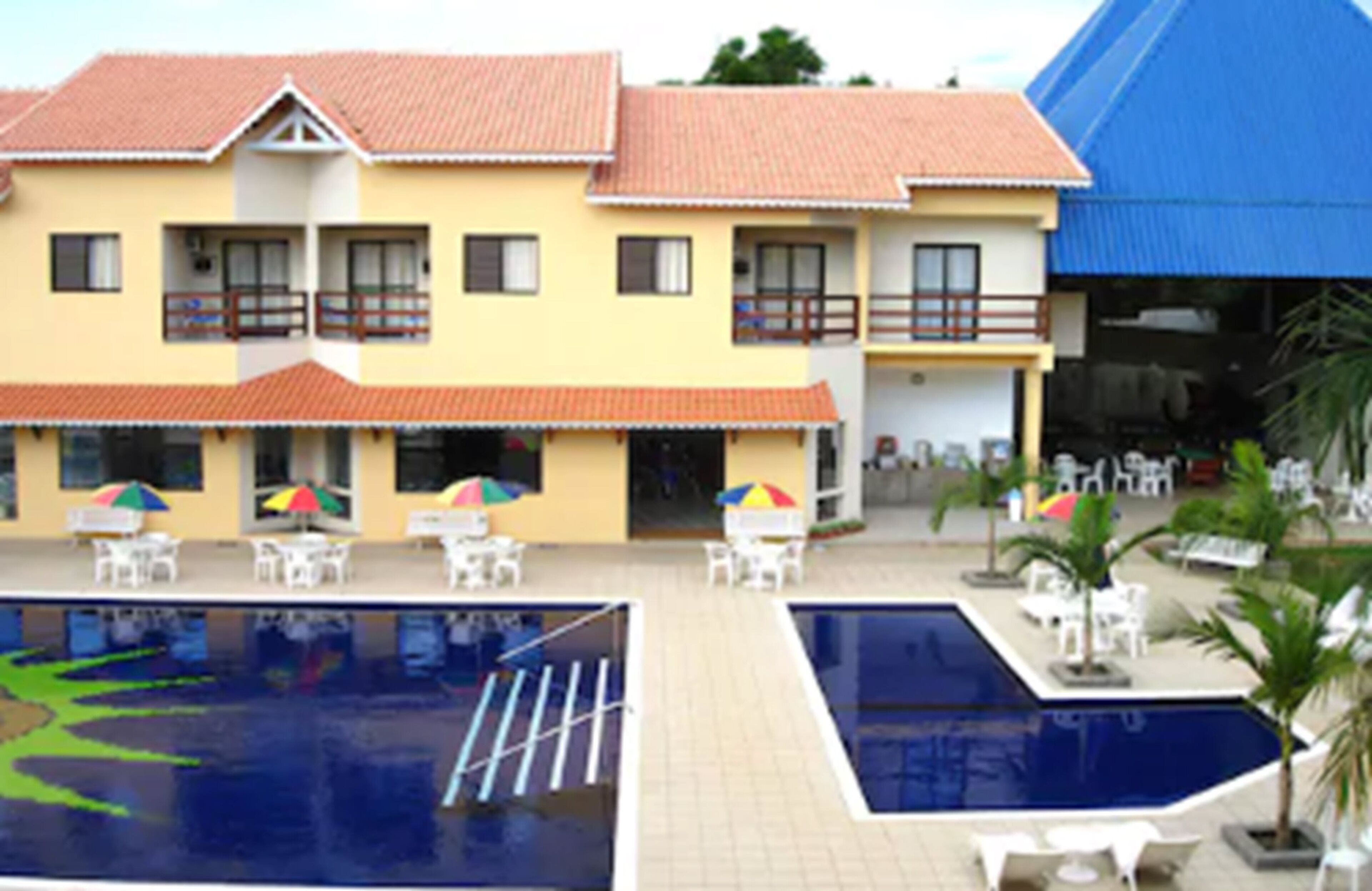 Um hotel com piscina, área de estar externa e um edifício com telhado azul.