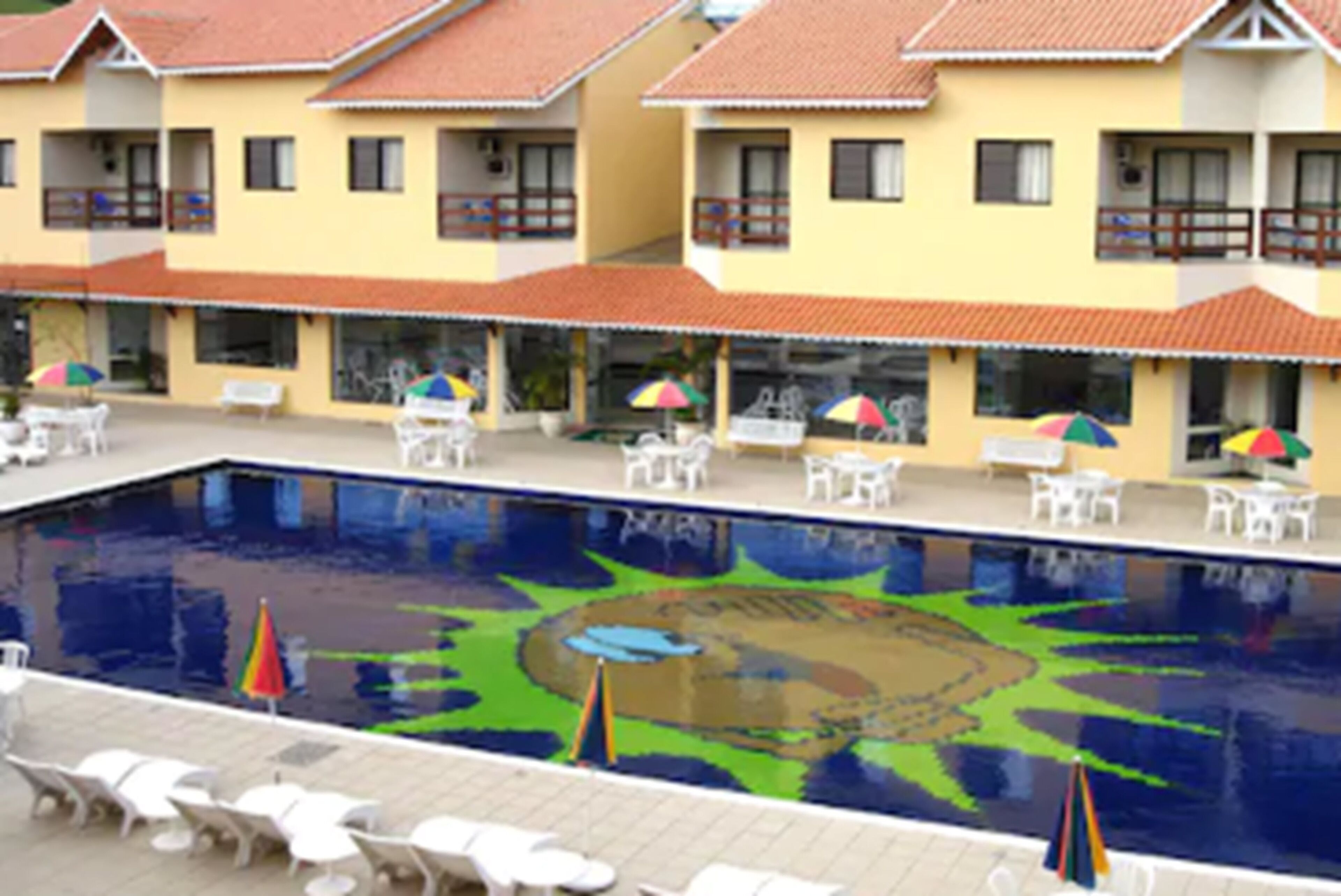 Hotel com piscina, área de estar ao ar livre e um mural colorido na superfície da piscina.