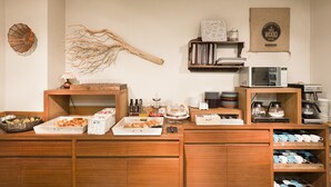 Disposição de buffet com diversos alimentos, uma máquina de café e um micro-ondas nas prateleiras.