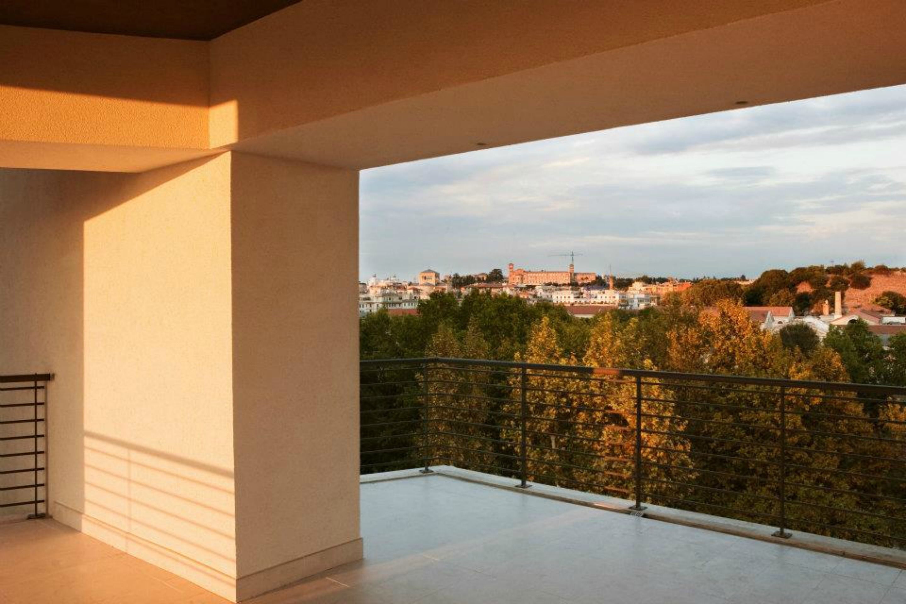 Uma varanda com vista para um horizonte urbano, incluindo edifícios e árvores.