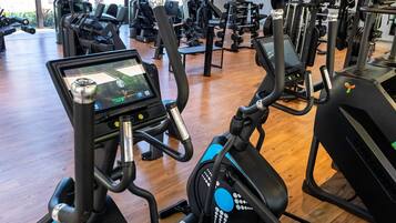 Uma academia com diversos equipamentos de exercícios, incluindo esteiras e aparelhos de musculação, dispostos em fileiras.