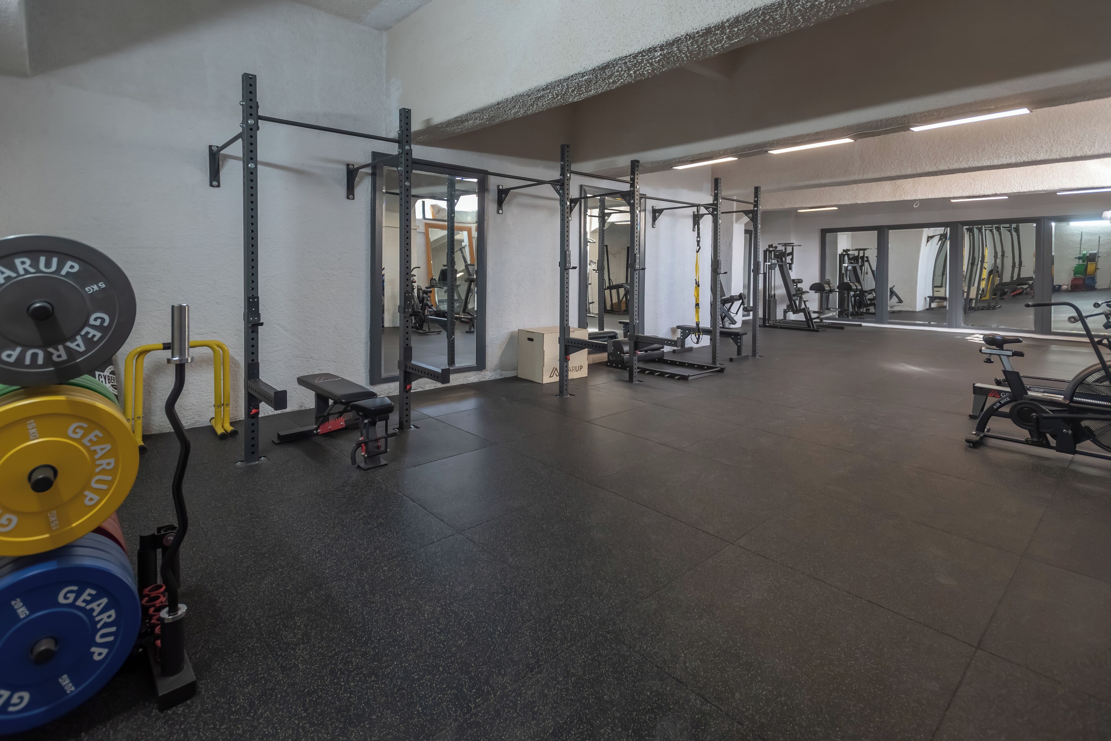 Uma academia com equipamentos de musculação, bancos e aparelhos de exercício.